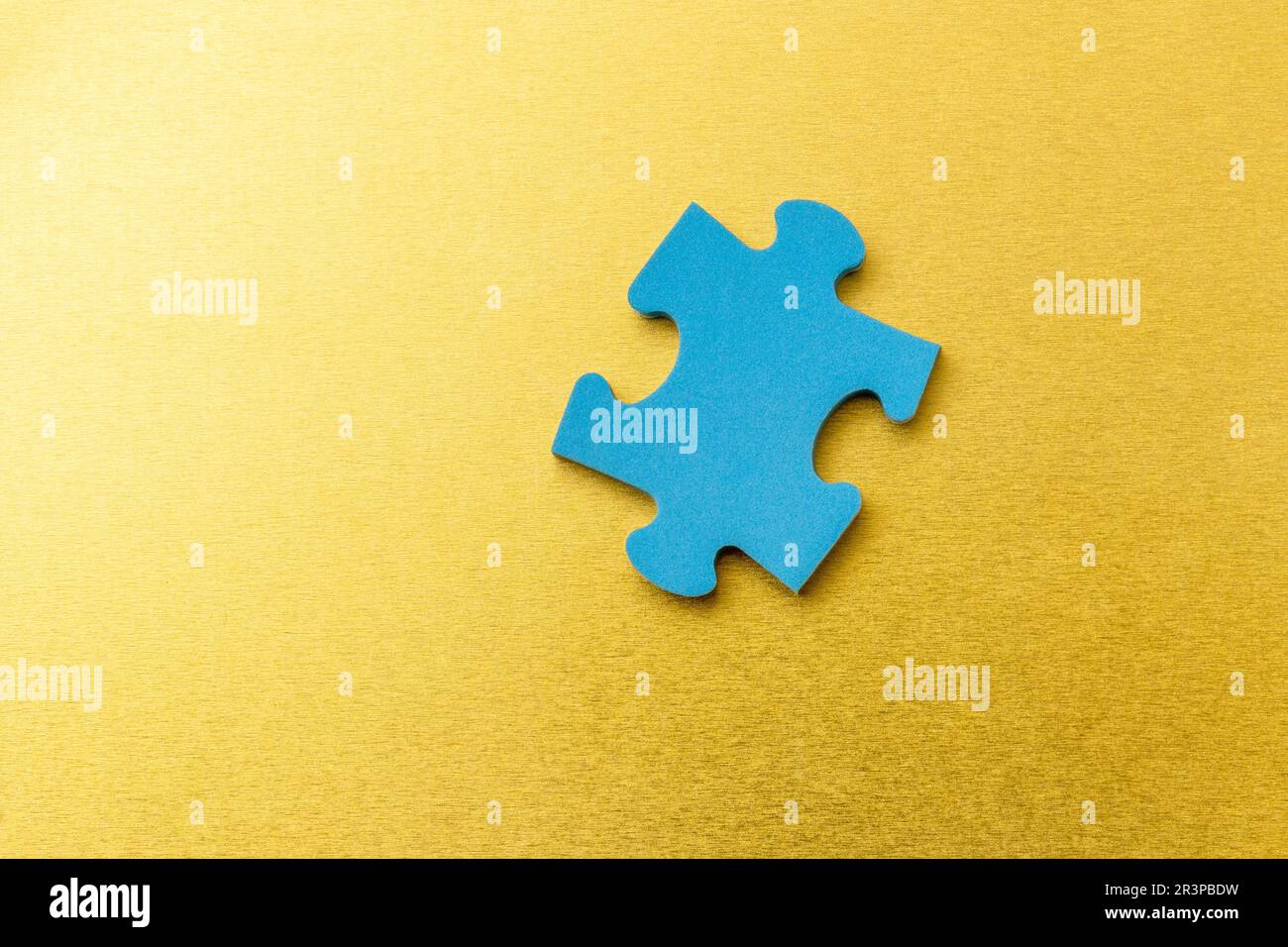 Single blue puzzle piece on a golden background Stock Photo - Alamy
