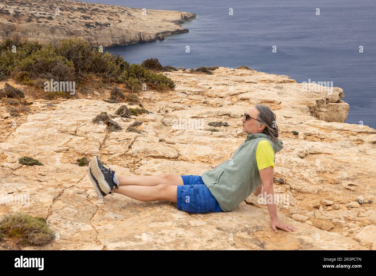On a steep seashore sits a male traveler, Crete, Greece Stock Photo - Alamy