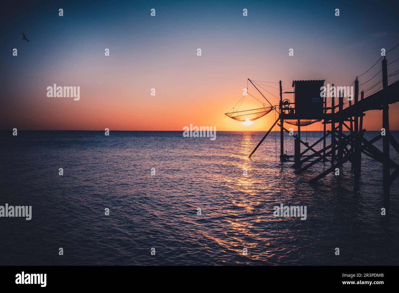 A fishing hut called carrelet with craft lifting net at sunset ...