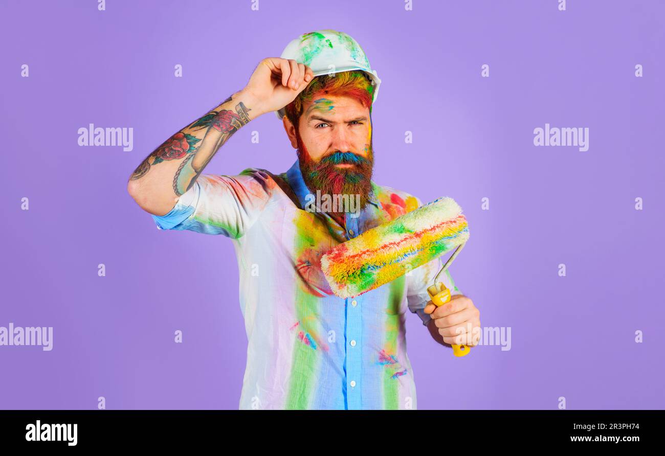 Painter in safety helmet with paint roller. Bearded painter in hardhat ...