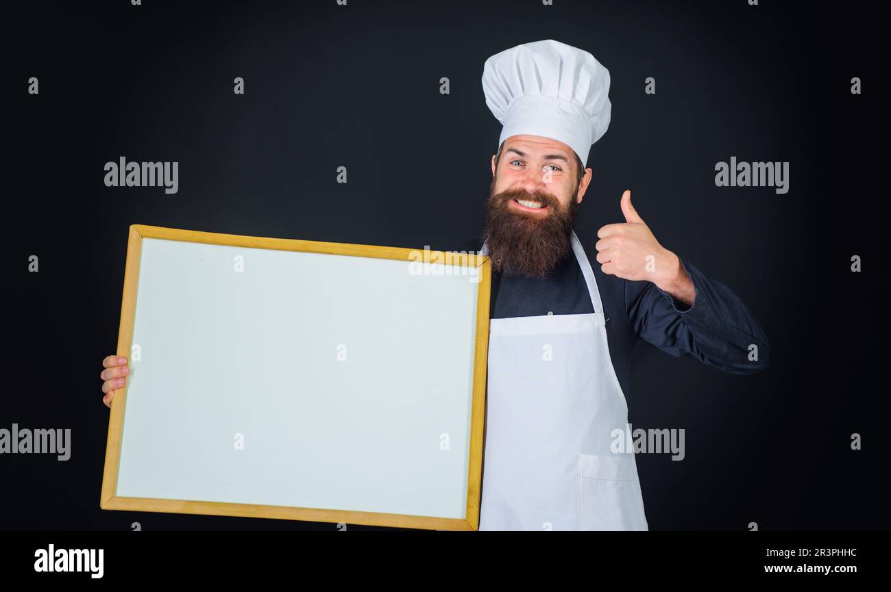 Smiling male chef, cook or baker with blank board showing thumb up ...