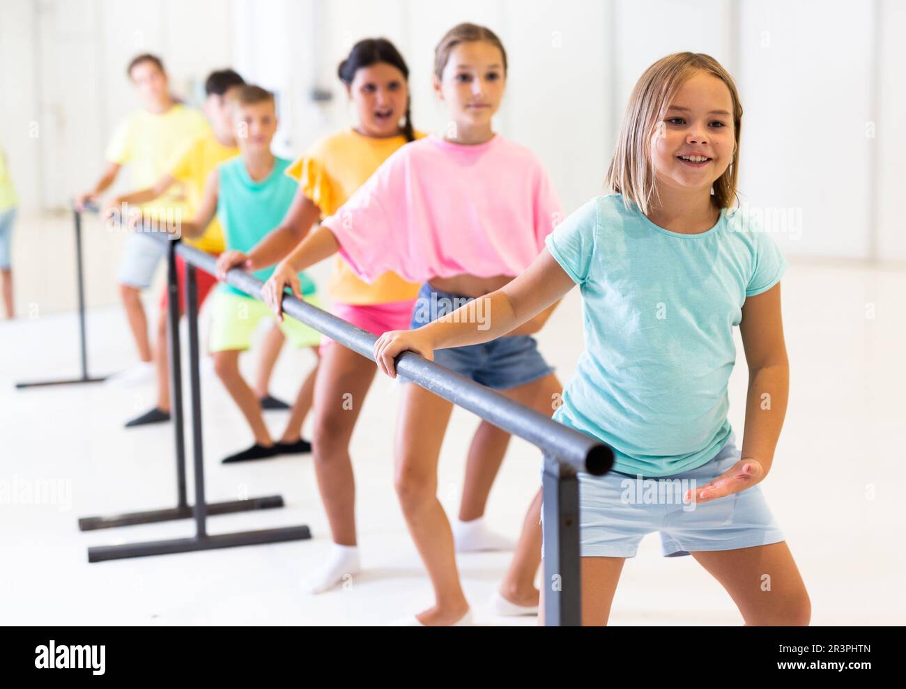 Children standing along ballet bar in dance studio during dance class ...