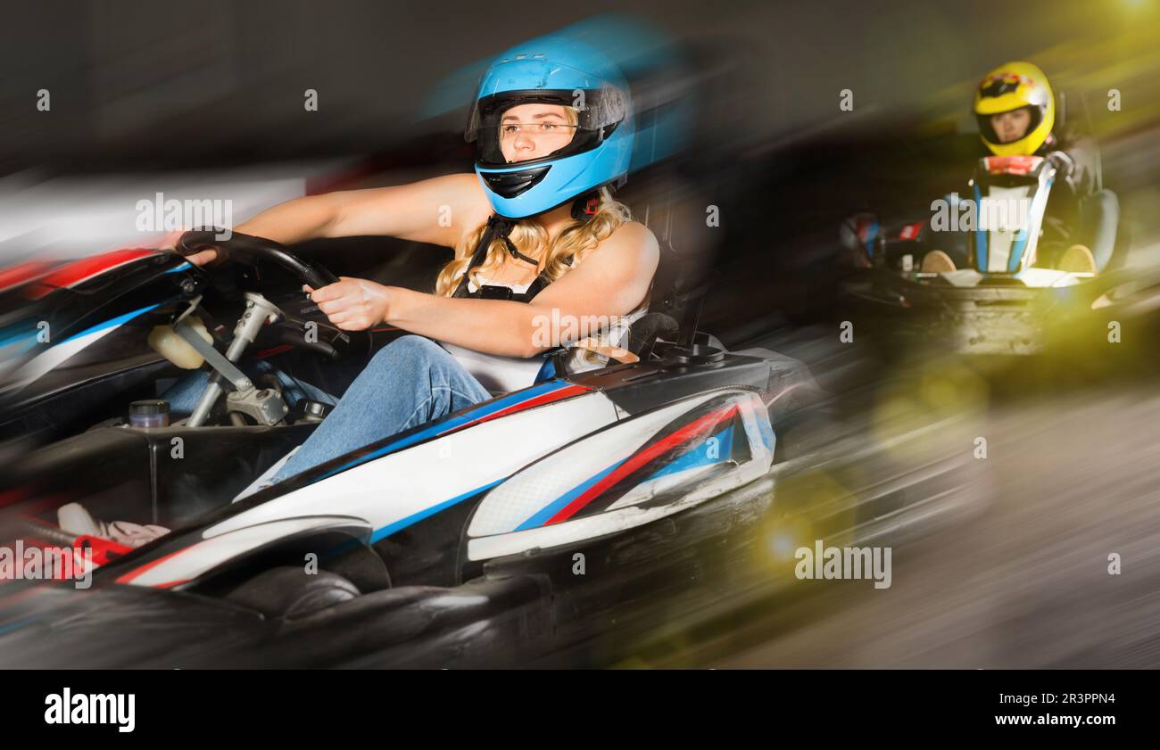 Girl and her friends competing on racing cars at kart circuit Stock ...