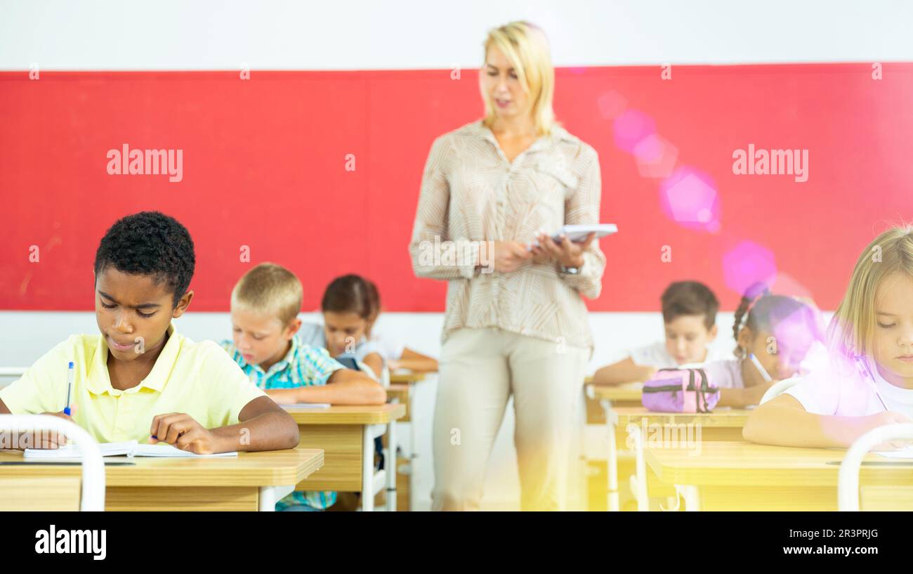 Teacher controlling learning process in primary school Stock Photo - Alamy