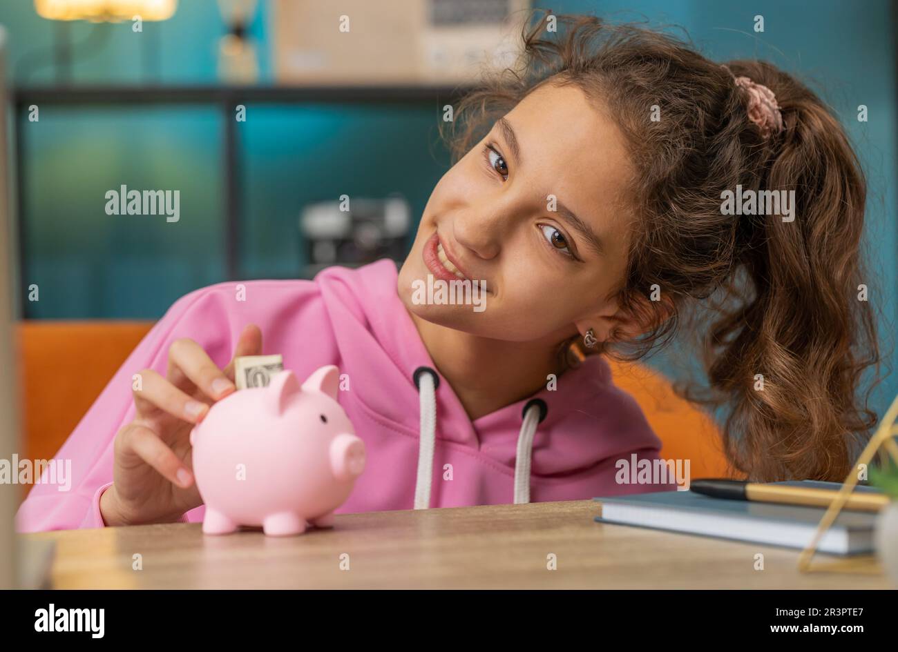 Caucasian preteen school girl putting one dollar cash money into piggy ...