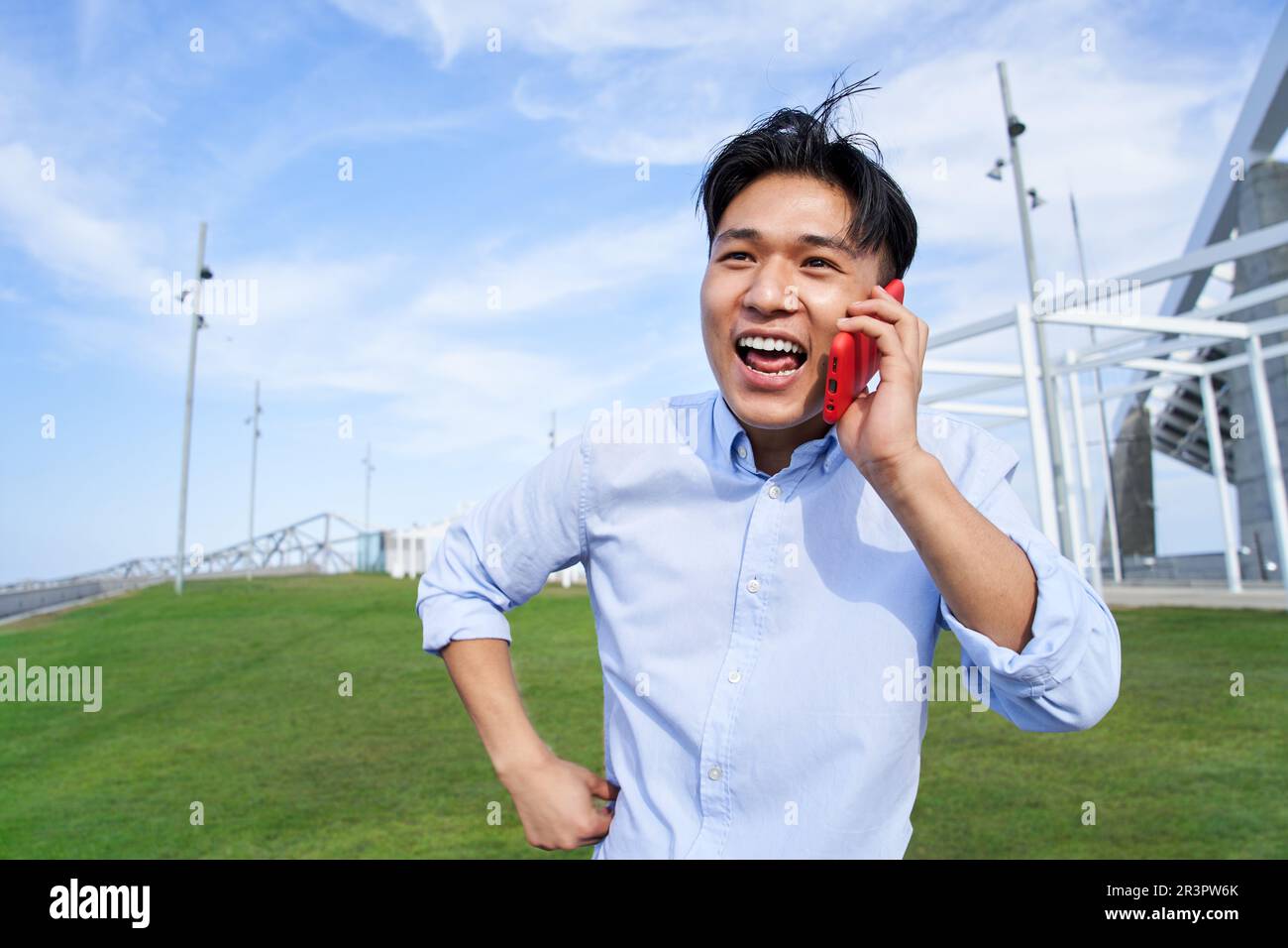Chinese cheerful boy talking on mobile outdoors with grass in ...