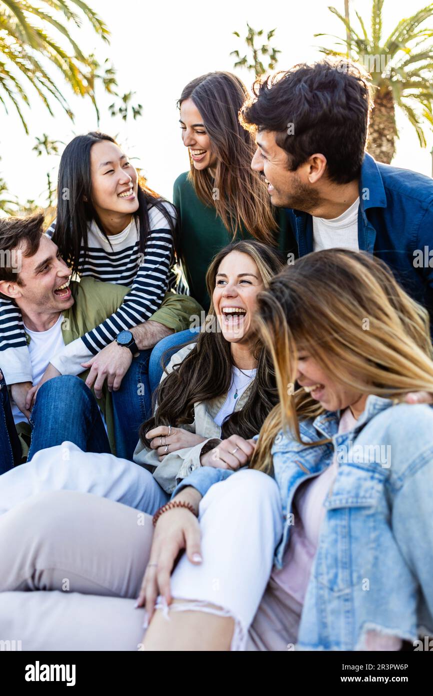 Vertical photo of happy group of millennial friends having fun sitting ...