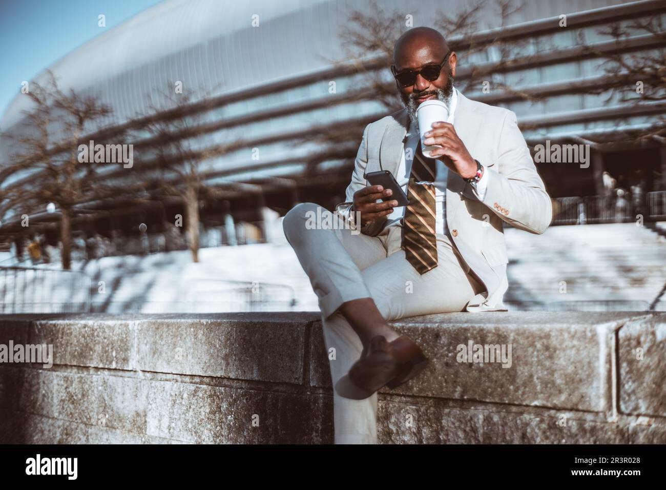 A bald black man sits on stone steps, wearing a suit, with a content ...
