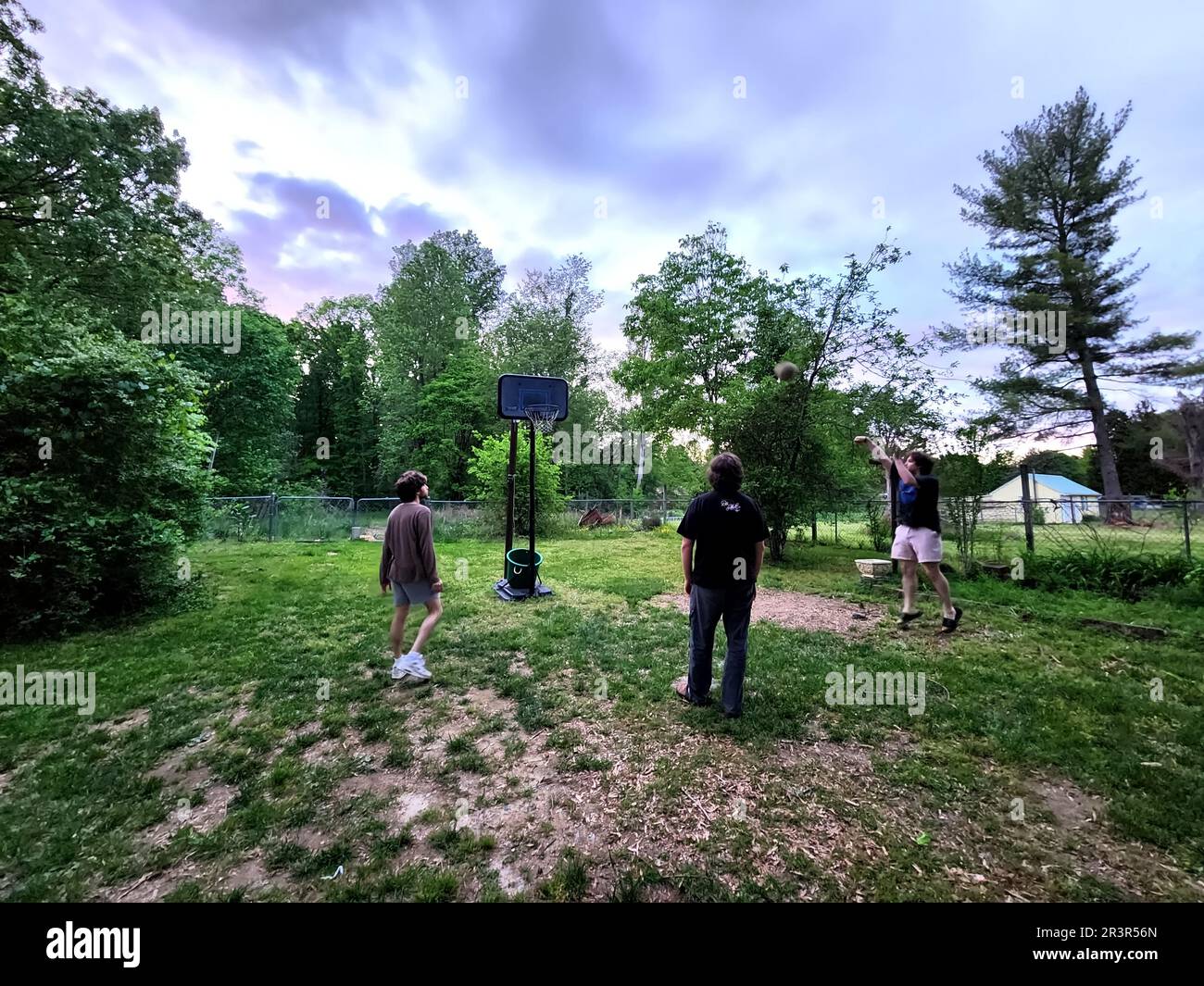 Three men playing basketball outside in a backyard Stock Photo - Alamy