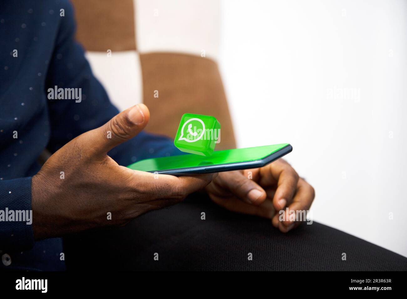 Black Hand holding mobile phone with WhatsApp logo hovering on screen ...