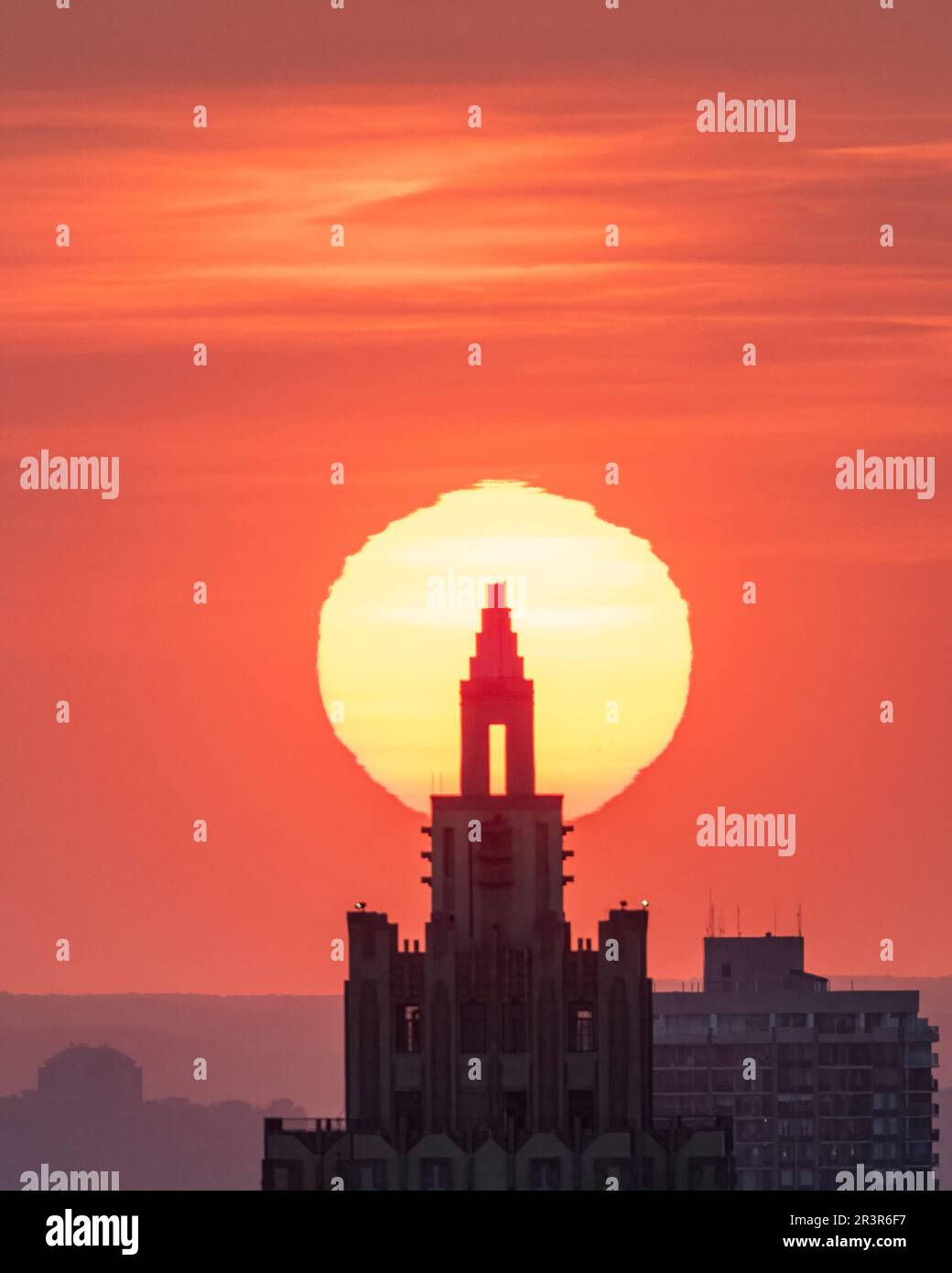 Huge sun setting between New York City towers Stock Photo - Alamy