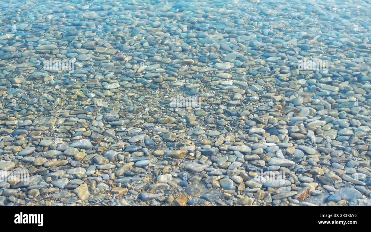Photo of a calm transporent water surface with pebbles stone under ...