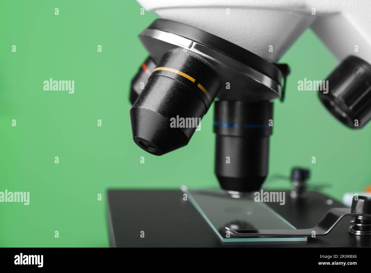 Modern medical microscope with glass slide on green background, closeup ...