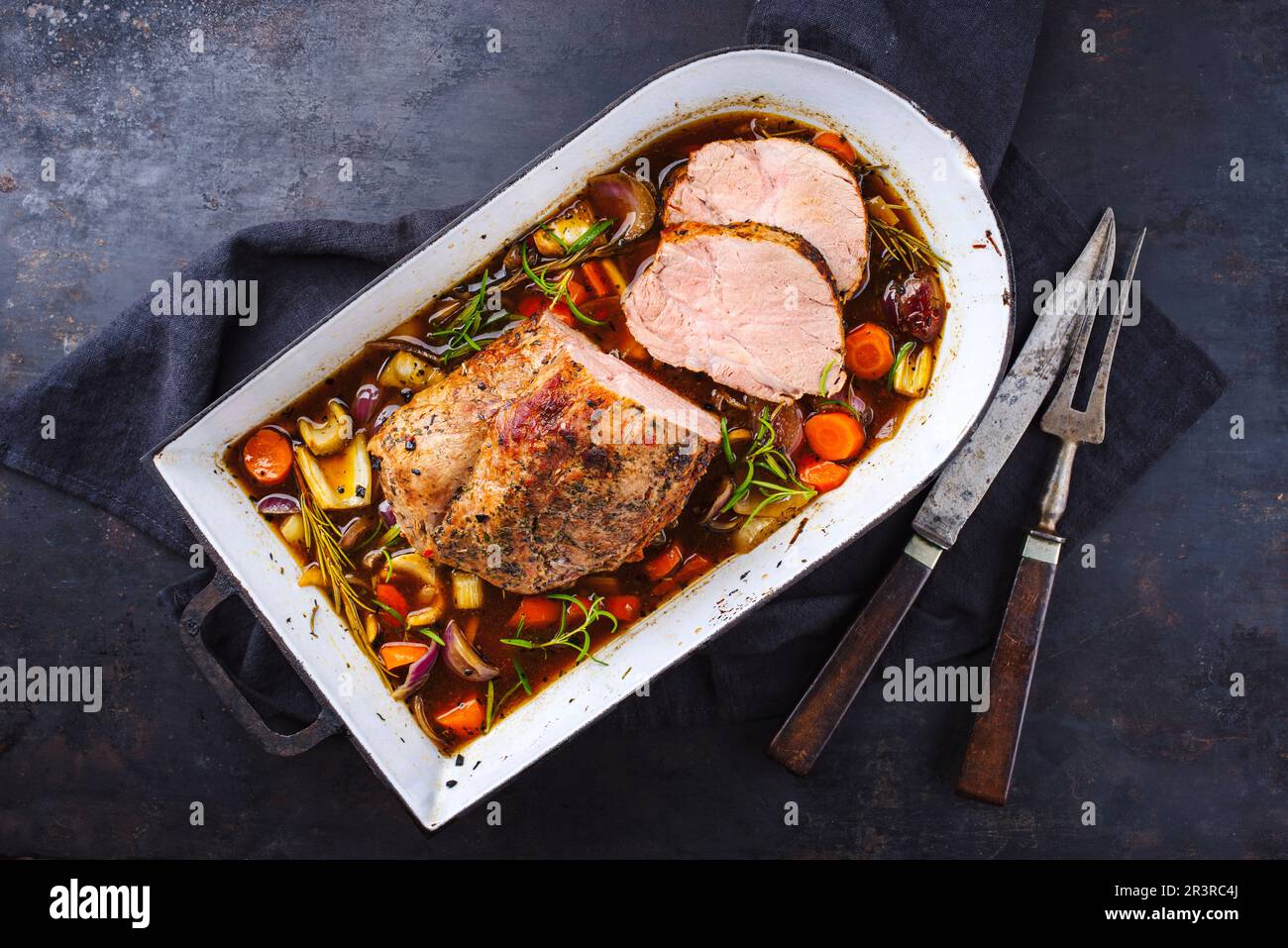 Traditional German pork roast served with vegetable and herbs in dark ...