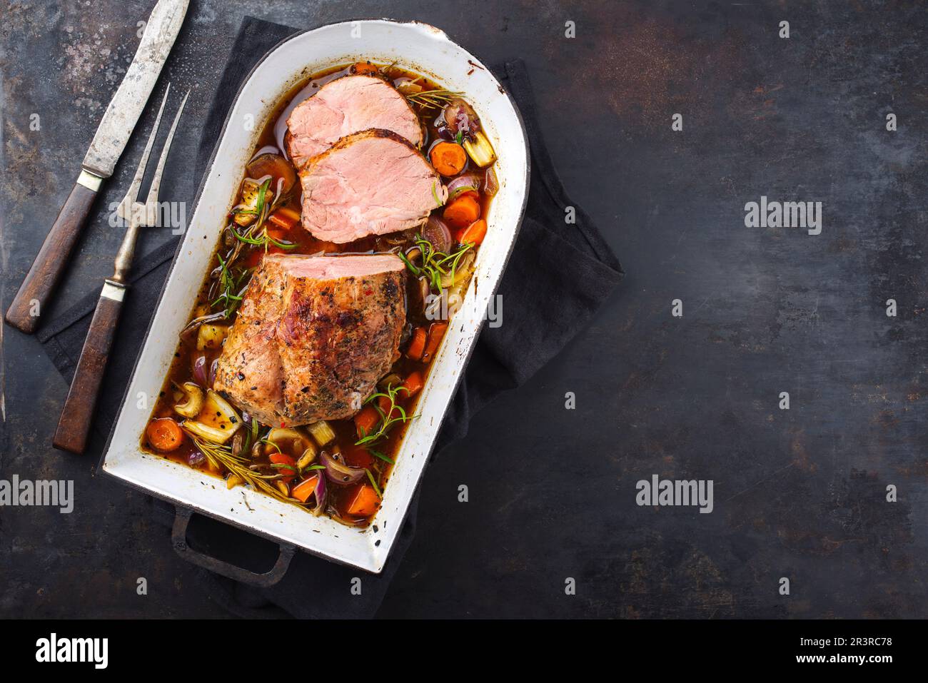 Traditional German pork roast served with vegetable and herbs in dark ...