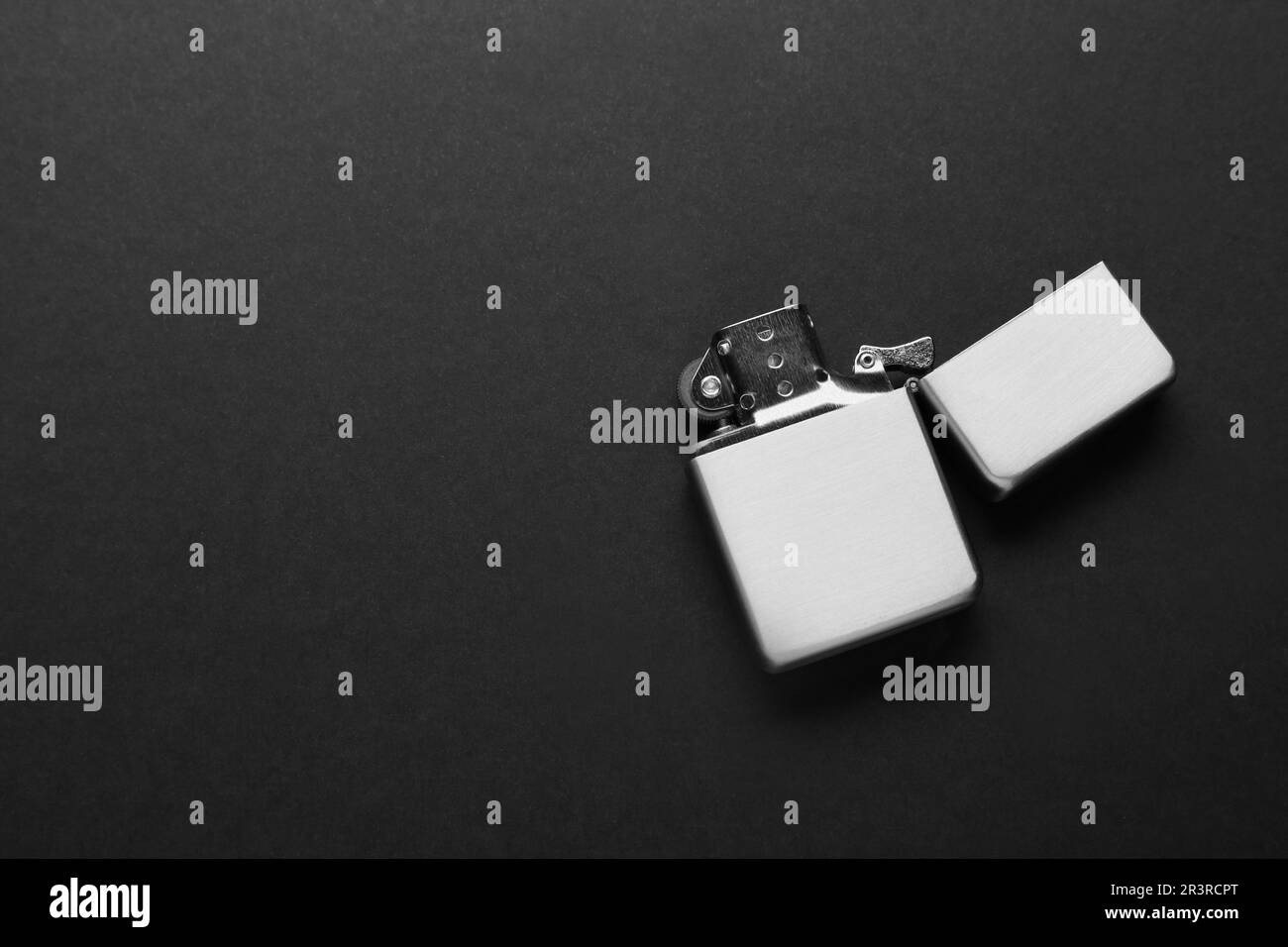 Gray metallic cigarette lighter on black background, top view. Space ...