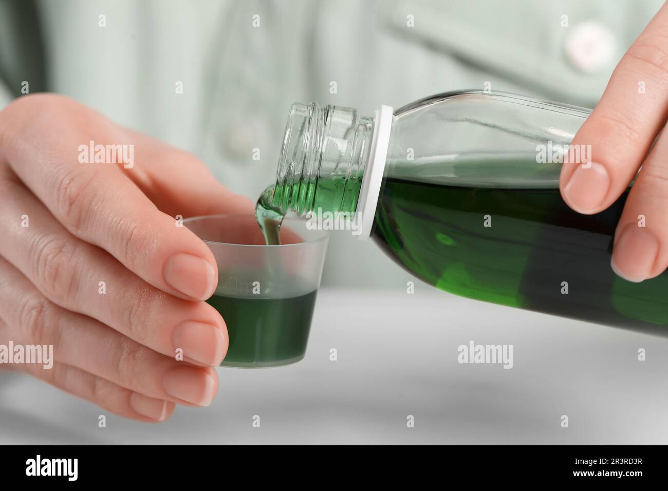 Woman pouring syrup from bottle into measuring cup at table, closeup ...