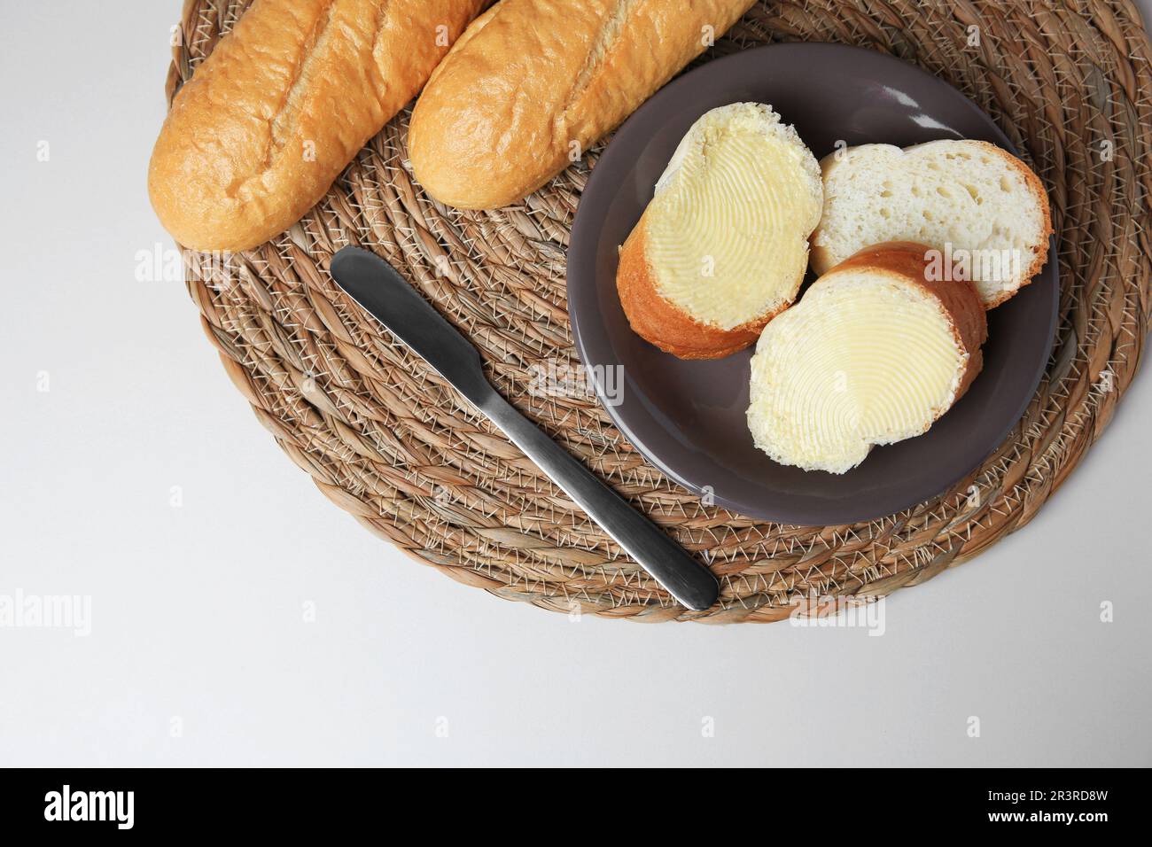 Whole and cut baguettes with fresh butter on white table, top view ...
