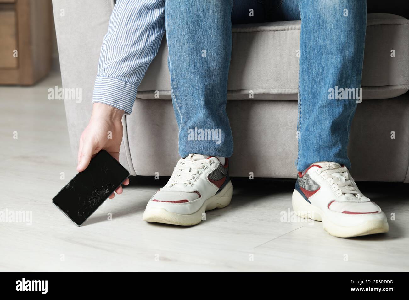 Man taking dropped smartphone from floor indoors, closeup. Device ...