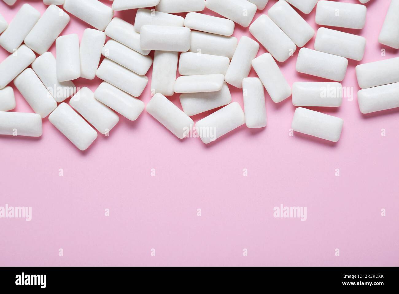 Tasty white chewing gums on pale pink background, flat lay. Space for ...