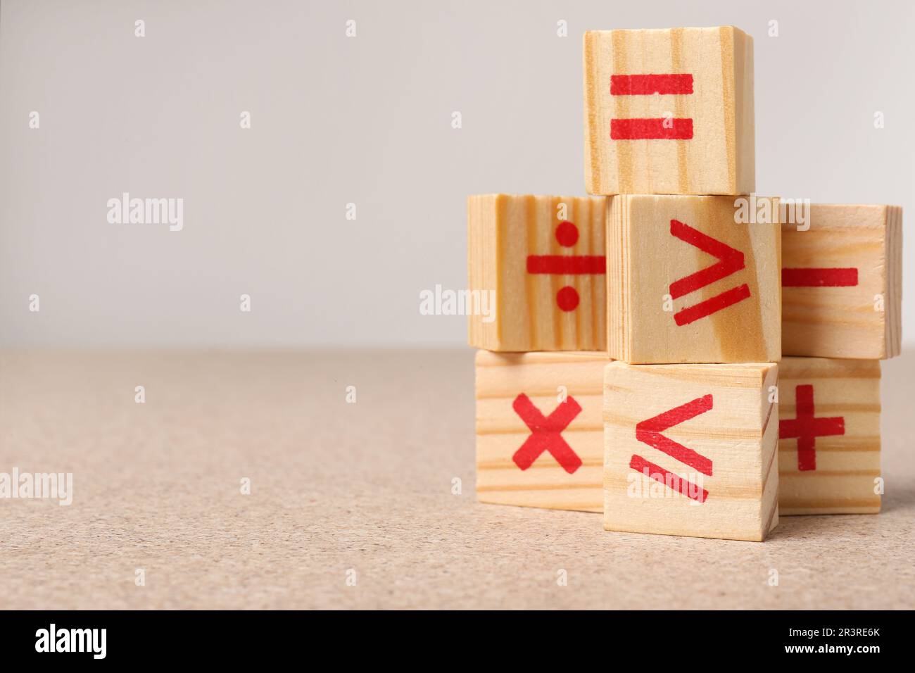 Wooden cubes with mathematical symbols on table against light ...
