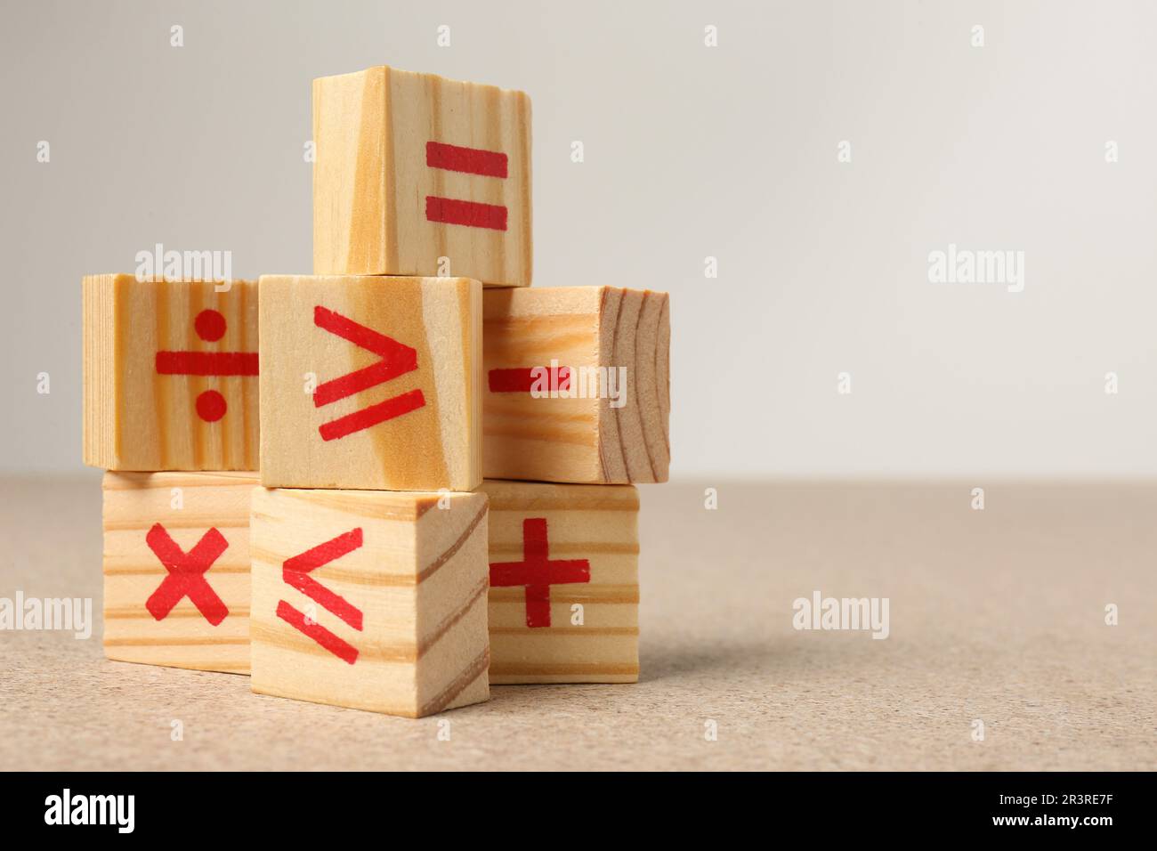 Wooden cubes with mathematical symbols on table against light ...