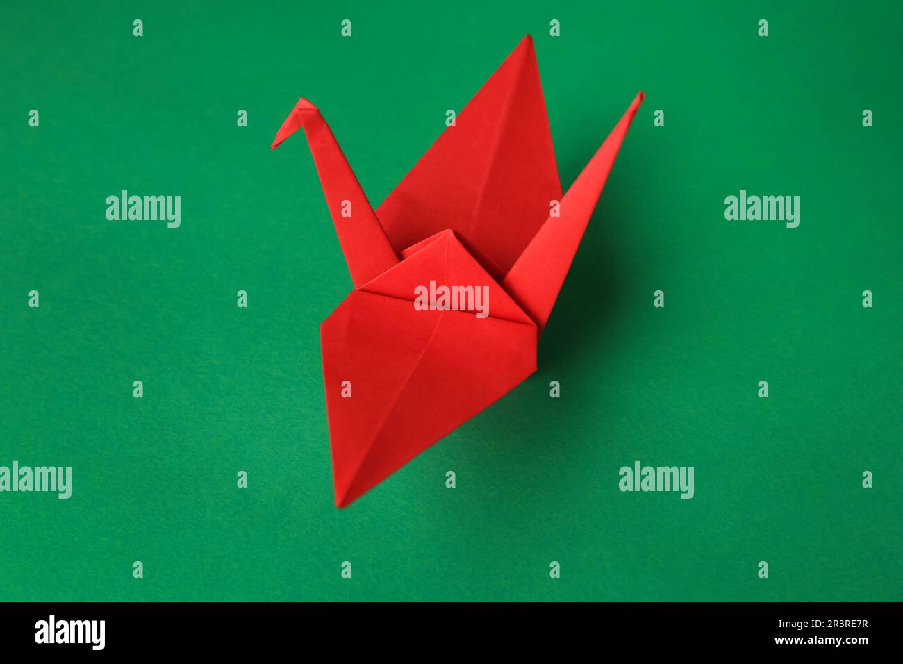 Red paper origami crane on green background Stock Photo - Alamy