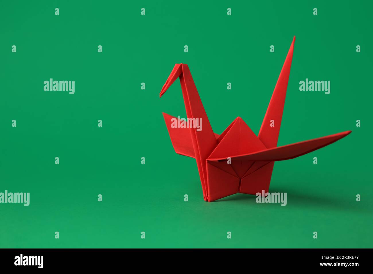 Red paper origami crane on green background, space for text Stock Photo ...