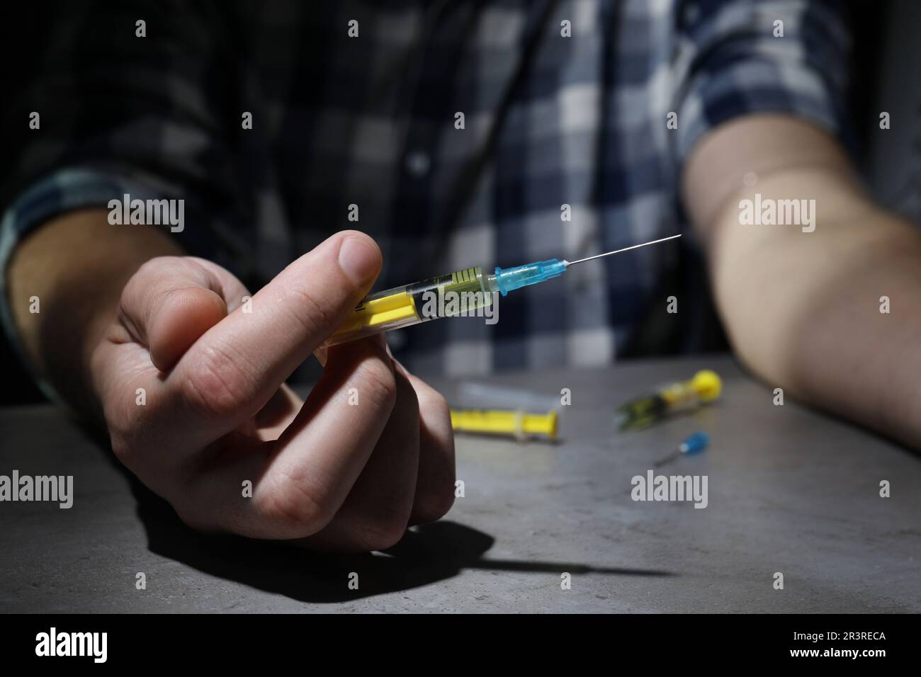 Drug addiction. Man with syringe at grey table, closeup Stock Photo - Alamy