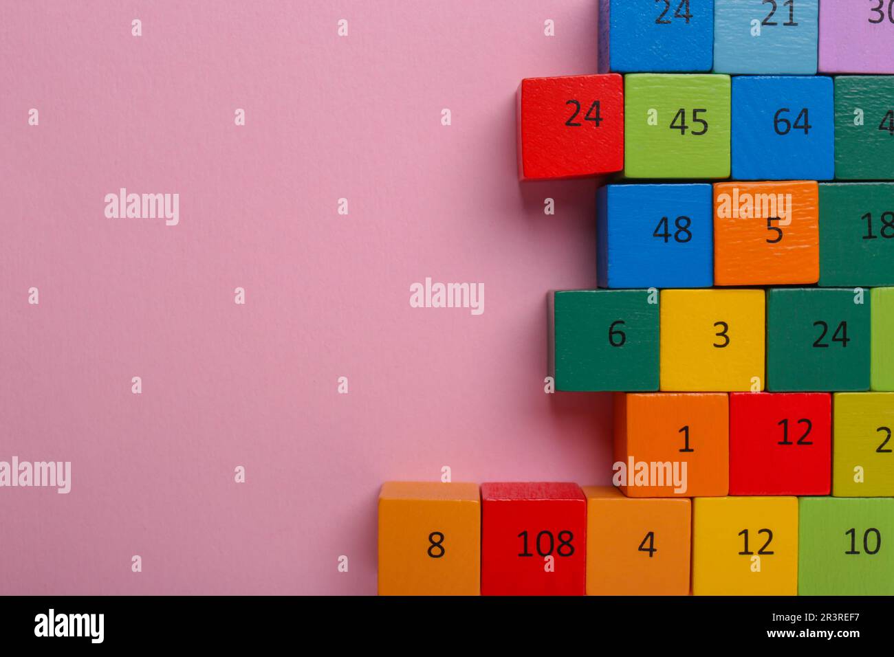 Wooden cubes with different numbers on light pink background, flat lay ...