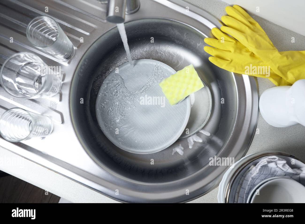 Washing plates, sponge and rubber gloves in kitchen sink, above view ...