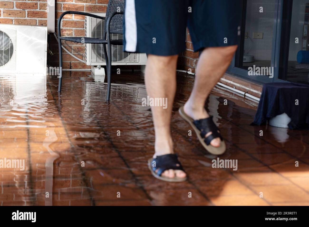 A man cleaning flooded balcony balcony after heavy rain Stock Photo - Alamy