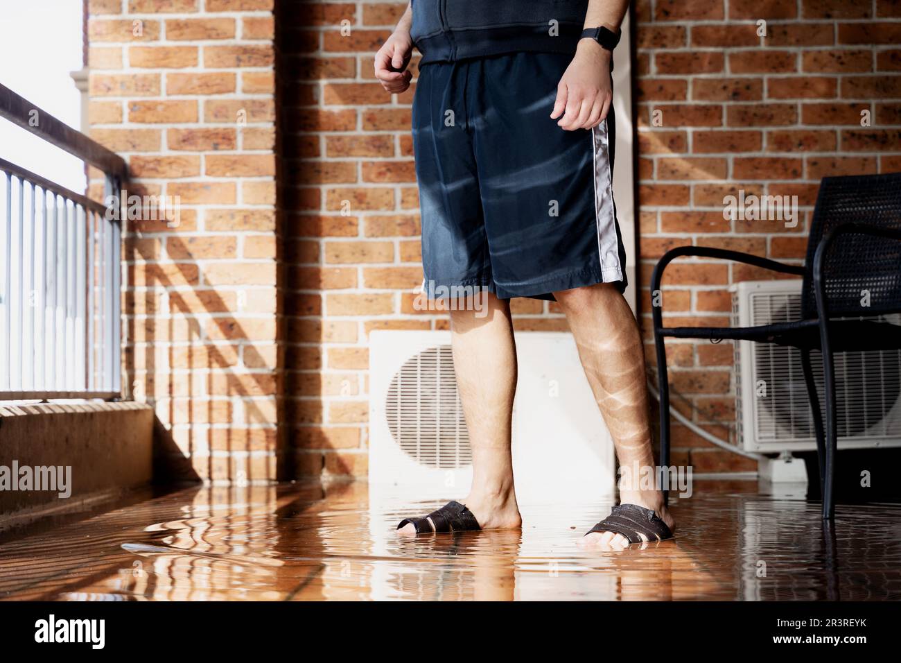 A man cleaning flooded balcony balcony after heavy rain Stock Photo - Alamy
