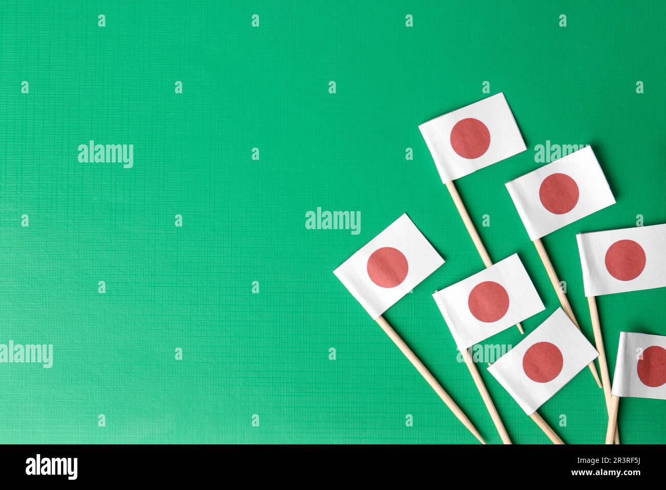 Small paper flags of Japan on green background, flat lay. Space for ...