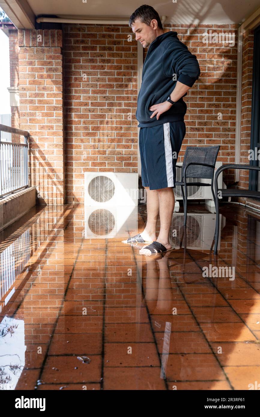 A man cleaning flooded balcony balcony after heavy rain Stock Photo - Alamy
