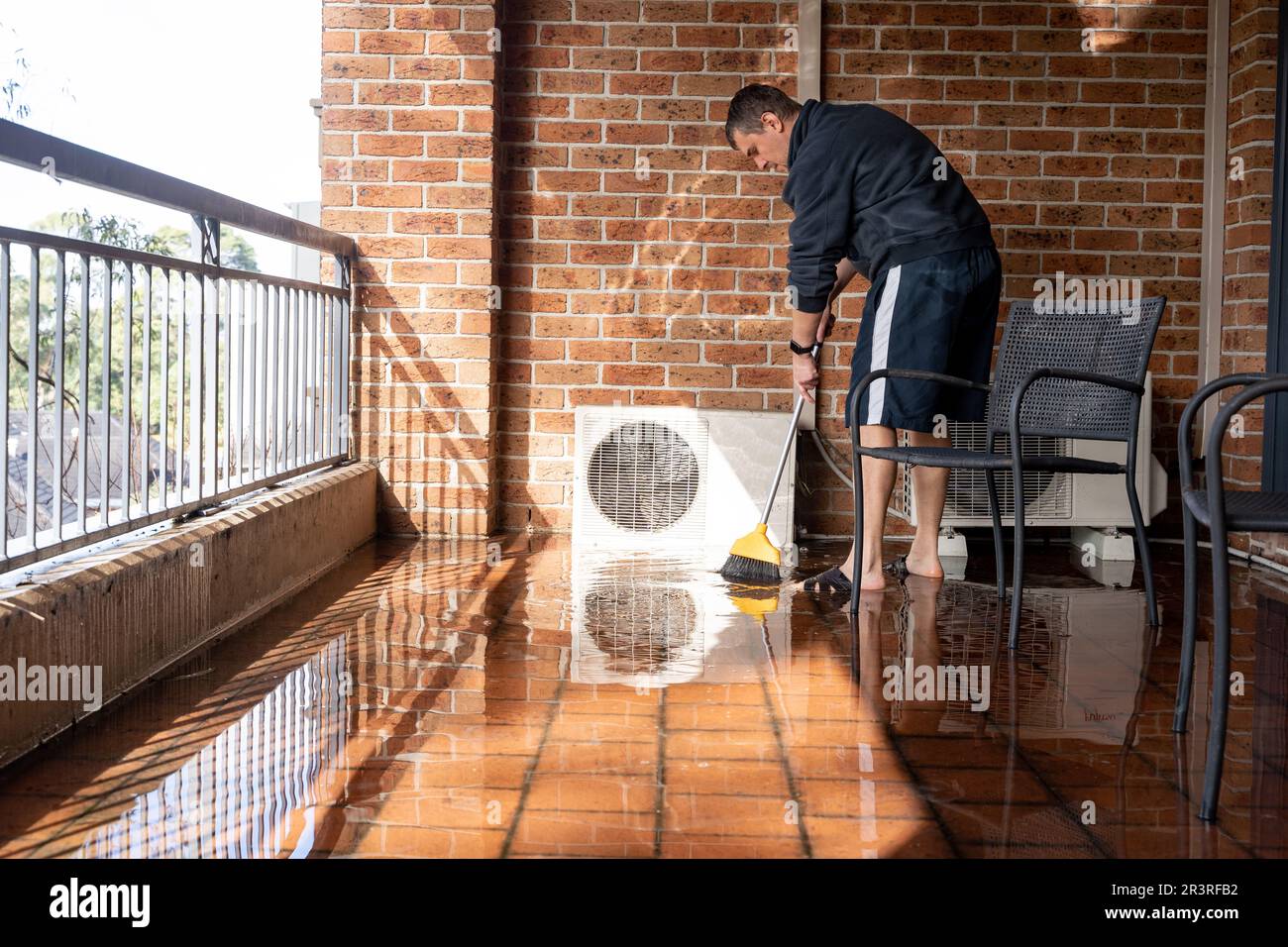 A man cleaning flooded balcony balcony after heavy rain Stock Photo - Alamy