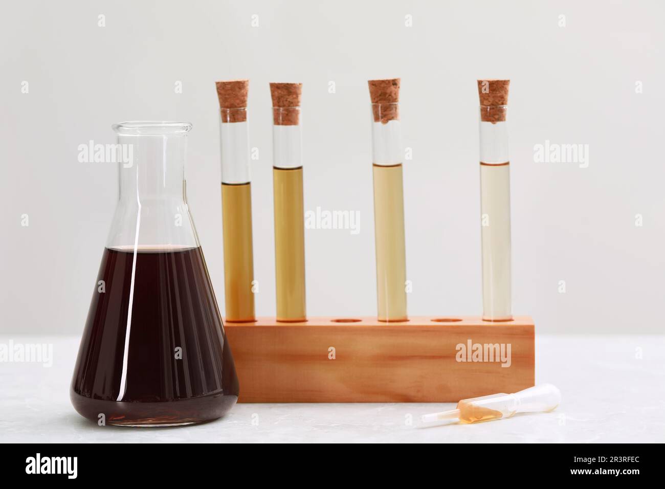 Laboratory glassware with brown liquids on table against light ...