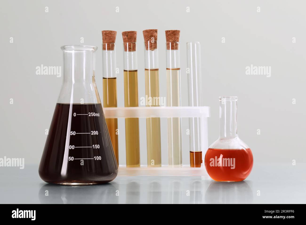 Different laboratory glassware with brown liquids on table against ...