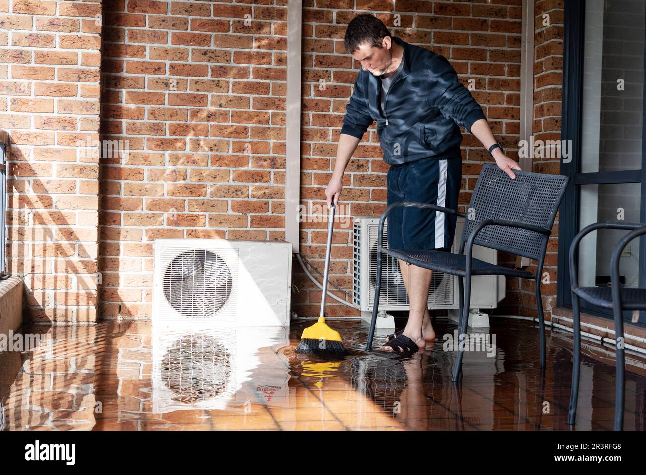 A man cleaning flooded balcony balcony after heavy rain Stock Photo - Alamy
