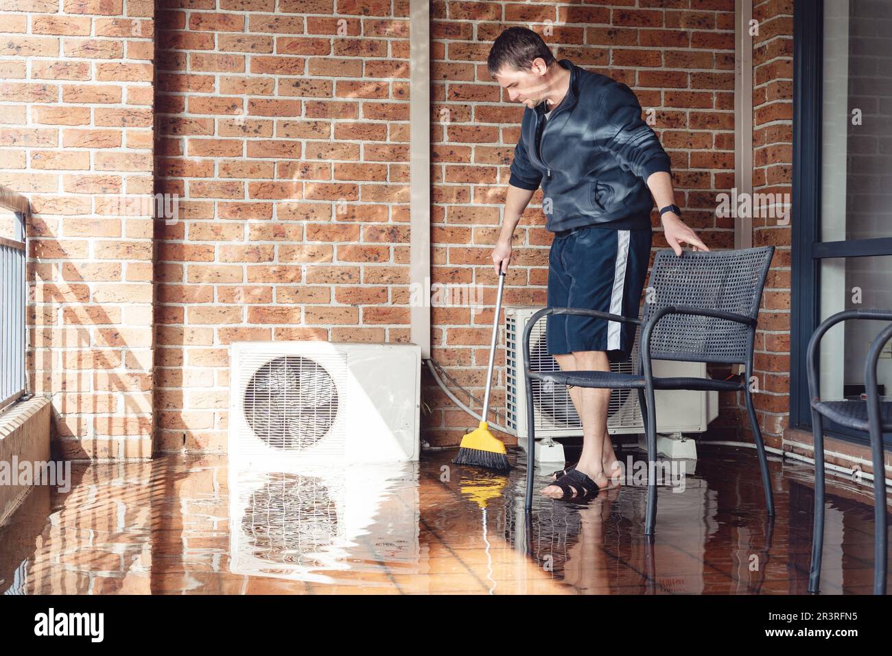 A man cleaning flooded balcony balcony after heavy rain Stock Photo - Alamy