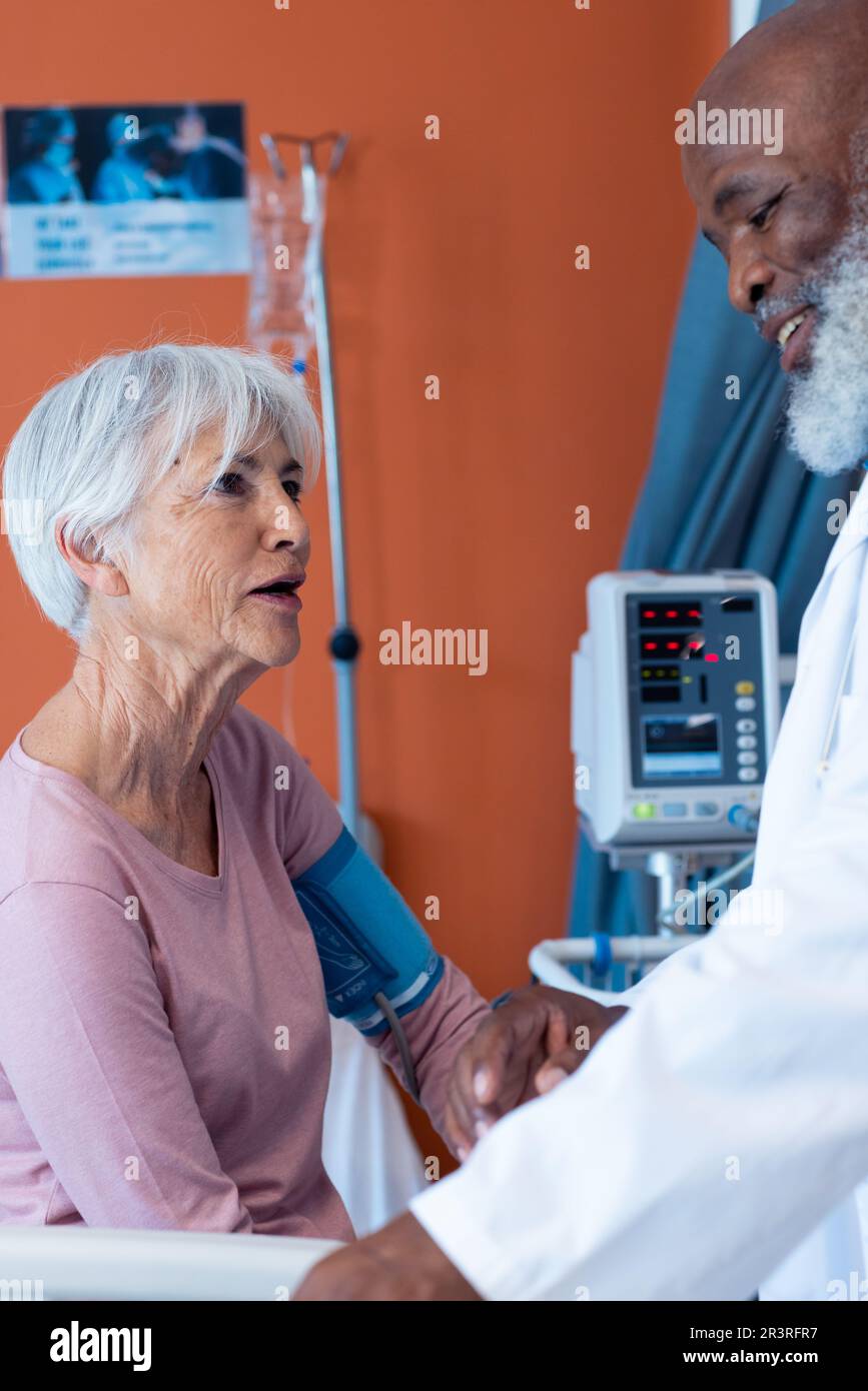 Vertical of happy diverse senior male doctor taking blood pressure of ...