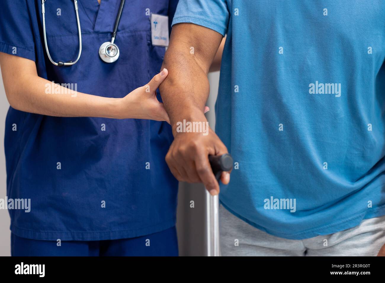 Midsection of diverse female doctor helping senior male patient use ...