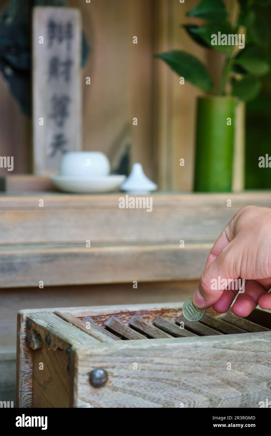 Hand making a offering in wooden offering box or Saisen Box, in ...