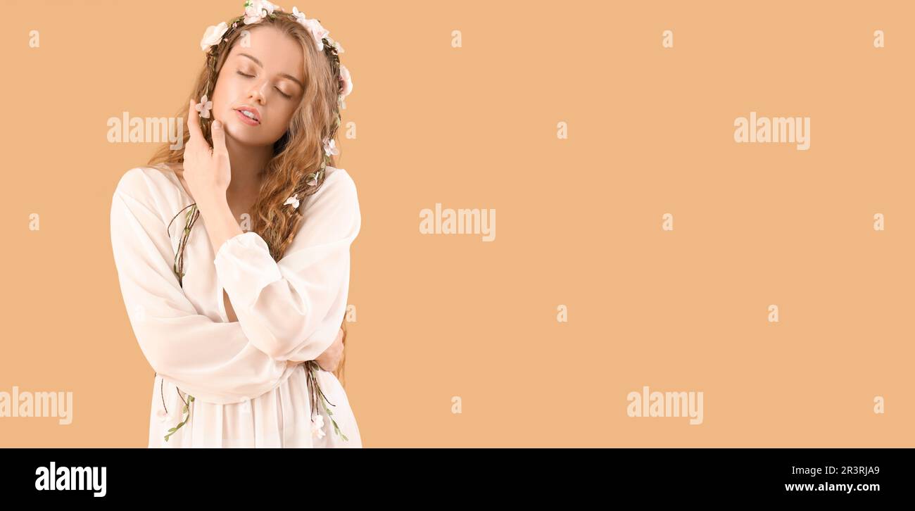 Beautiful young woman with flowers in her hair on beige background with ...