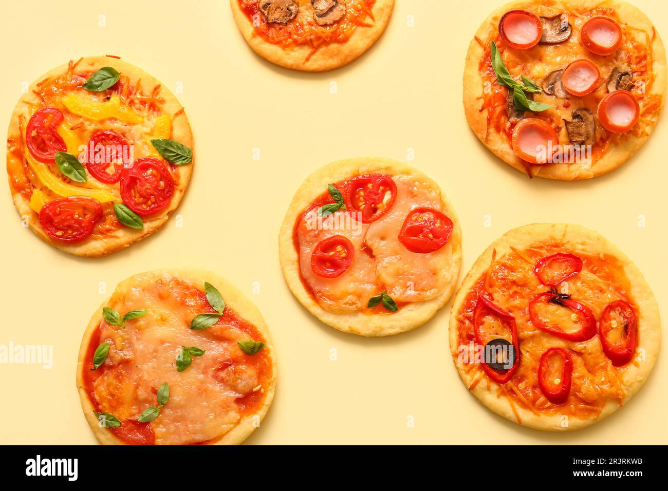 Different tasty mini pizzas on yellow background Stock Photo - Alamy