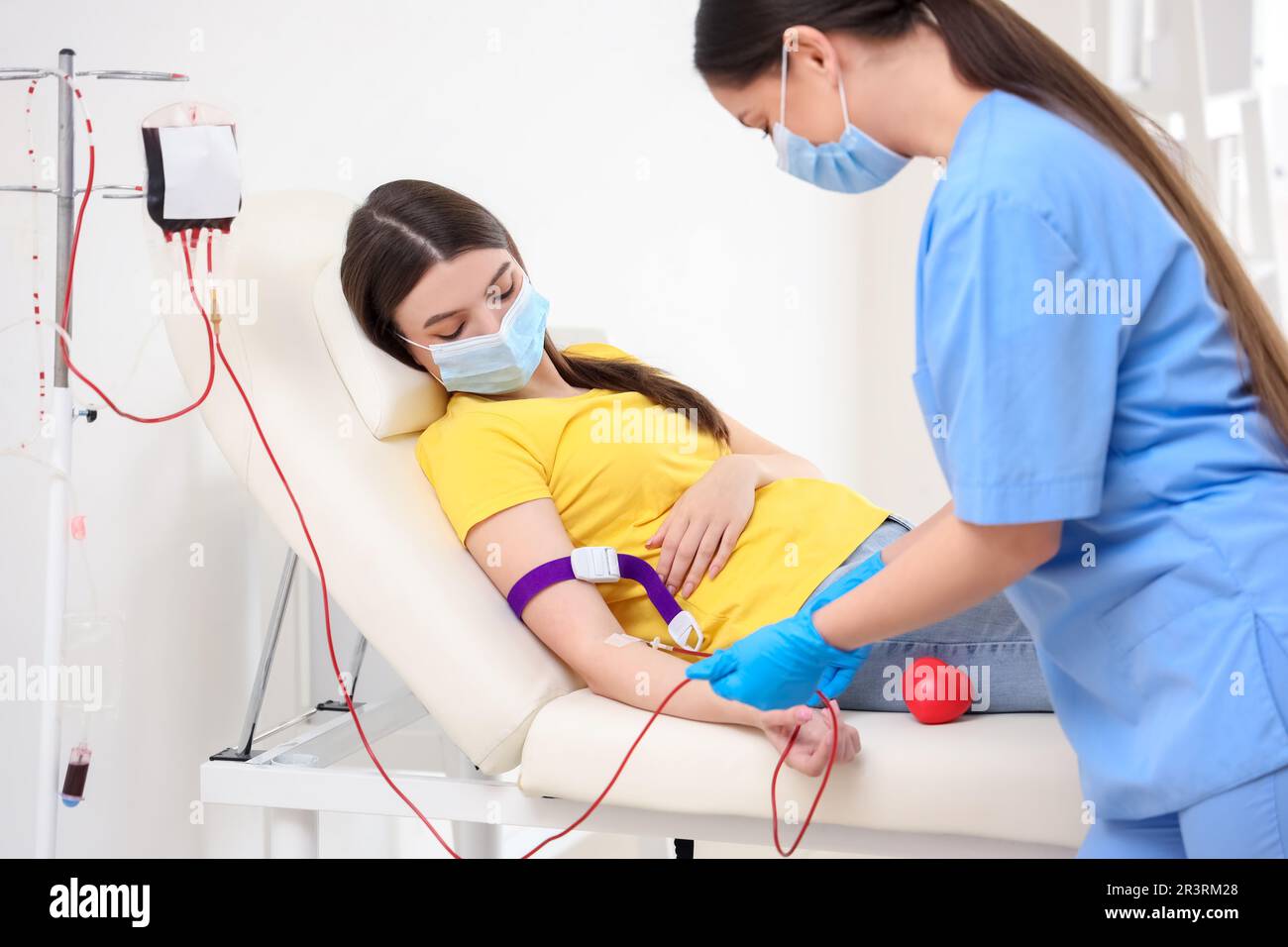 Female nurse taking blood from young donor in clinic Stock Photo - Alamy