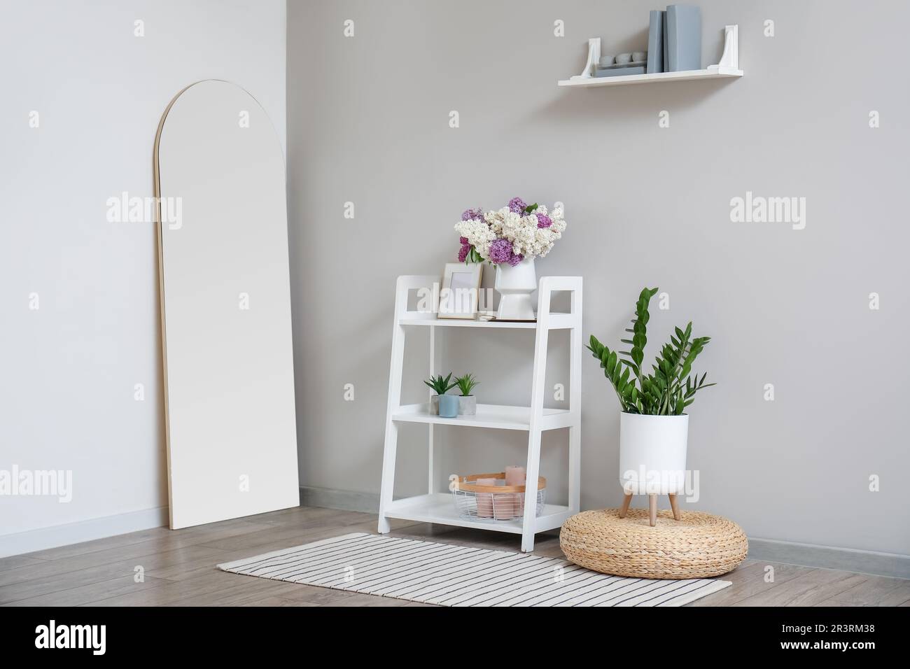 Interior of light room with lilac flowers in vase and shelving unit ...