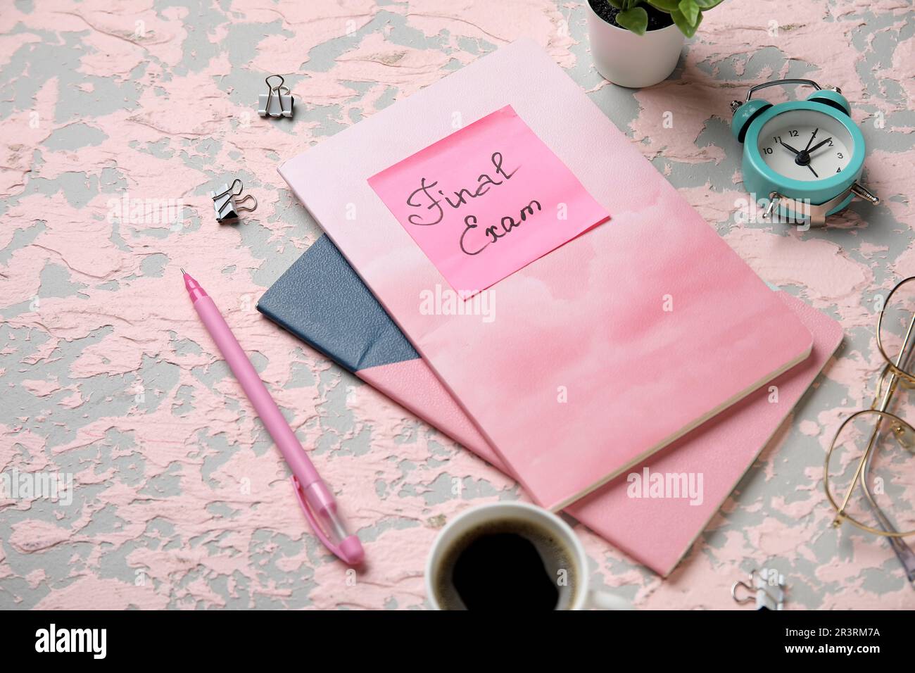 Sticky note with text FINAL EXAM, notebooks, alarm clock and cup of ...