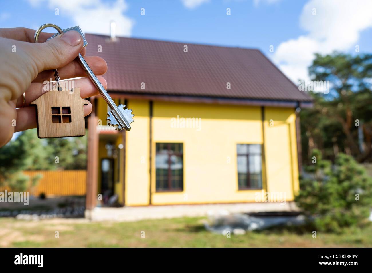 A hand with the keys to a new house on the background of an unfinished ...