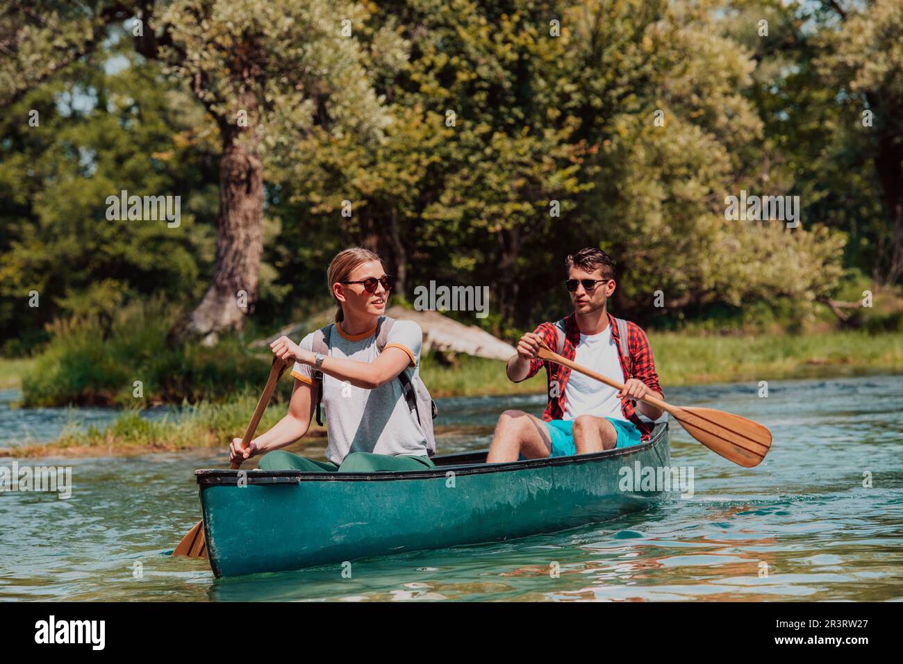 Couple adventurous explorer friends are canoeing in a wild river ...